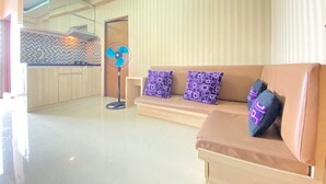 Uma sala de estar moderna com um sofá de couro marrom, um ventilador de chão e uma parede estampada.