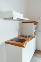 Uma cozinha compacta com uma pia de aço inoxidável, micro-ondas e forno embutido.