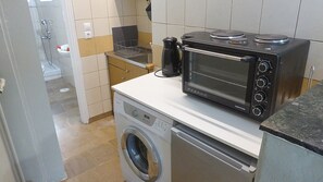 Cozinha compacta com máquina de lavar, micro-ondas e cafeteira.