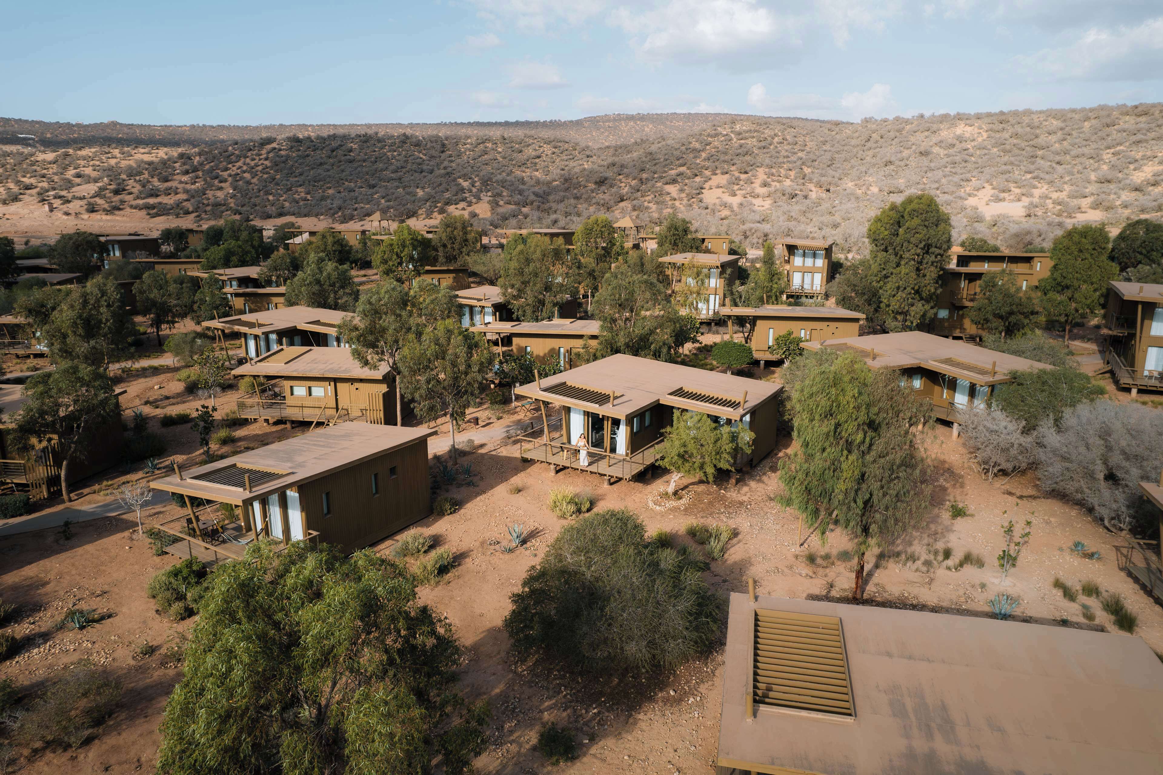 Um resort no deserto com vários edifícios de dois andares, cada um com teto plano e grandes janelas.