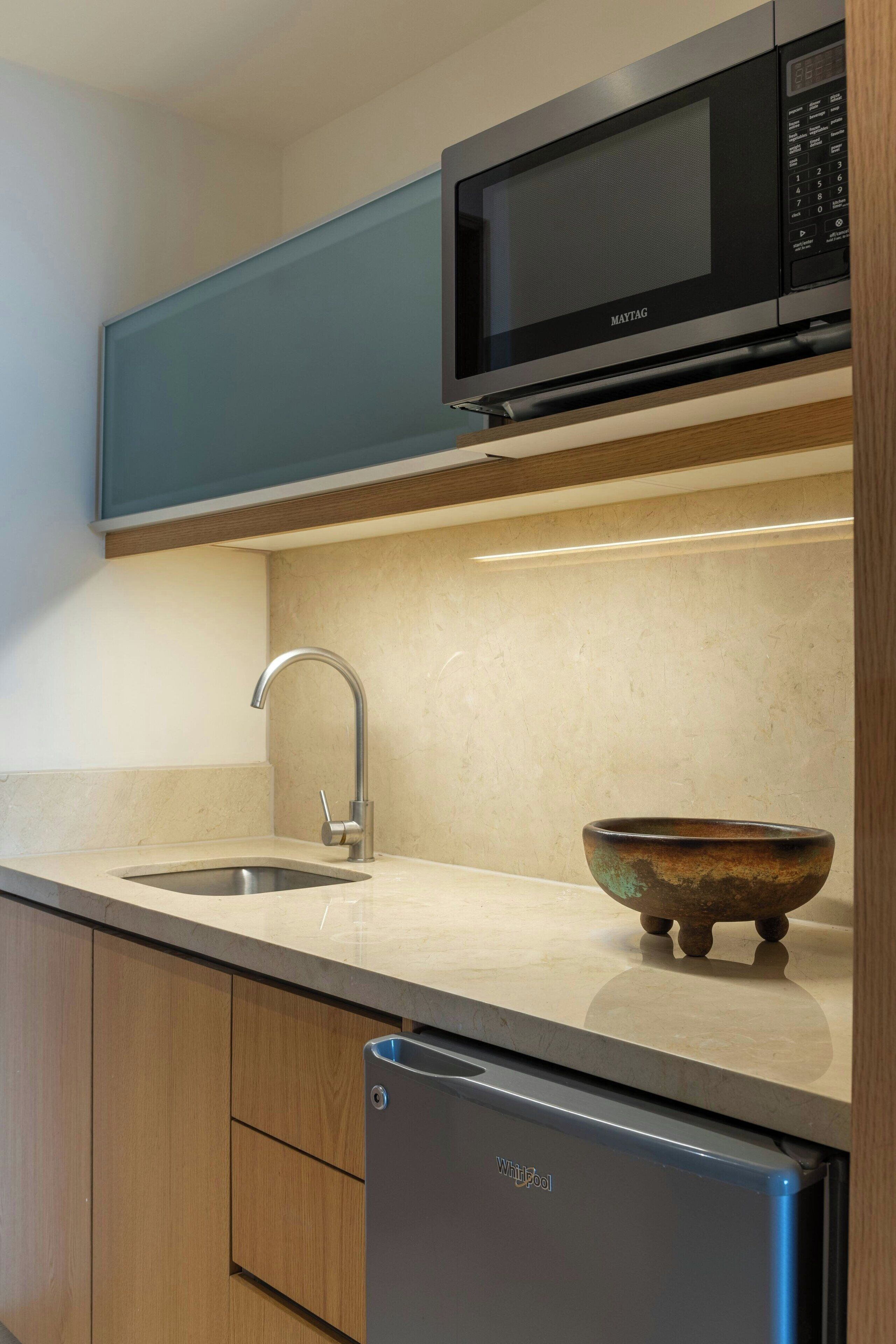 Uma cozinha moderna com micro-ondas embutido, pia de aço inoxidável e máquina de lavar louça.