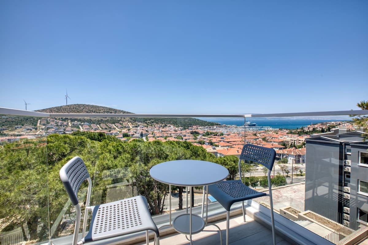 Varanda com mesa e cadeiras com vista para uma cidade costeira.