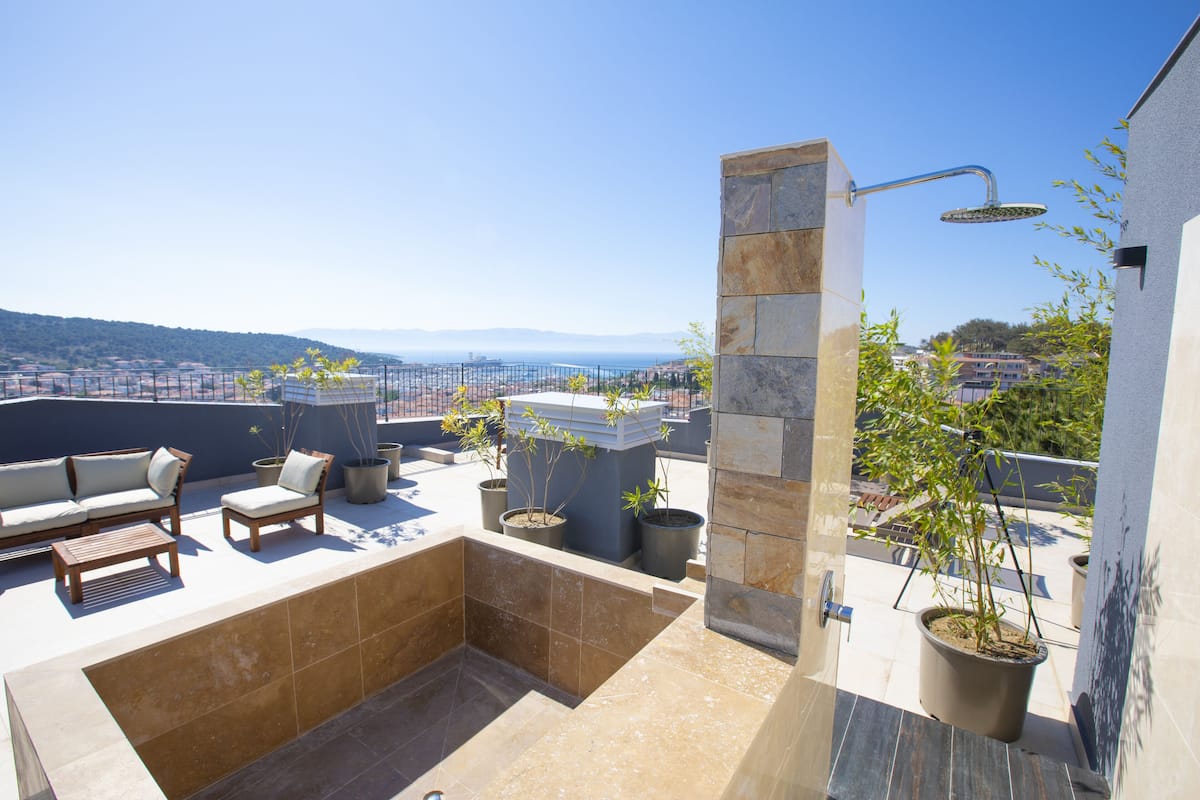 Terraço no telhado com área de estar, chuveiro embutido e plantas em vasos.