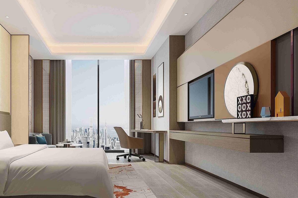 Quarto de hotel moderno com uma cama grande, uma escrivaninha e uma televisão. O quarto tem vista para a cidade e uma janela ampla.