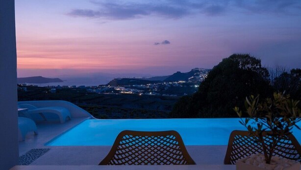 Vista do pôr do sol a partir de uma área externa com piscina, com vista para o horizonte urbano e colinas.