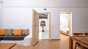 Interior moderno com sofá, mesa de jantar e vista através de uma porta.