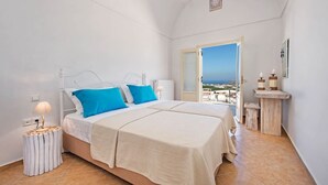 Quarto com cama, mesa de cabeceira, espelho e vista para o mar.