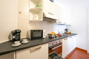 Uma cozinha compacta equipada com cafeteira, micro-ondas e forno.