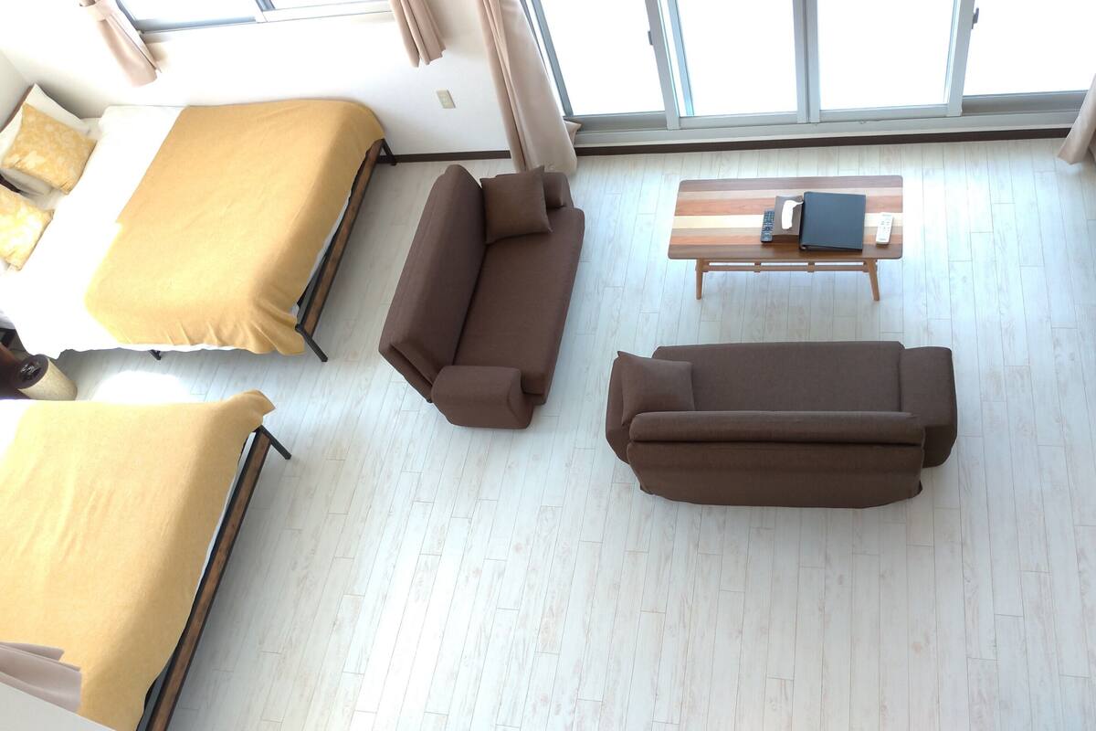 Uma sala de estar moderna com um sofá, uma mesa de centro e uma cama com cobertura amarela.