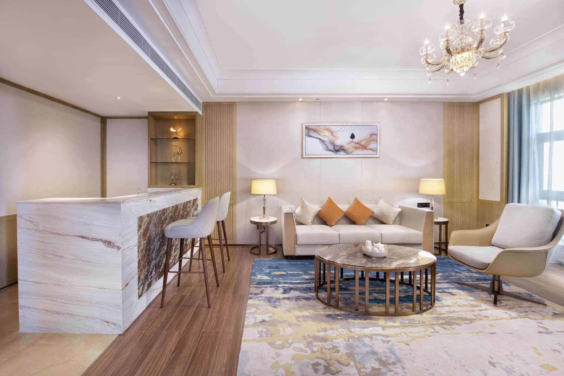 Quarto de hotel moderno com balcão de mármore, mesa de centro redonda e sofá com almofadas.