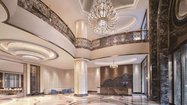 Um hall imponente com piso de mármore, um grande candelabro e um balcão de recepção.