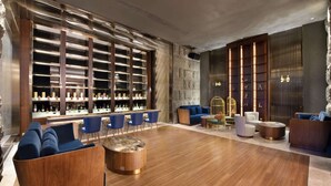 Uma área de estar moderna com bar, assentos e uma grande variedade de garrafas.