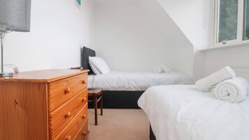 Quarto com cômoda de madeira, cama e janela.