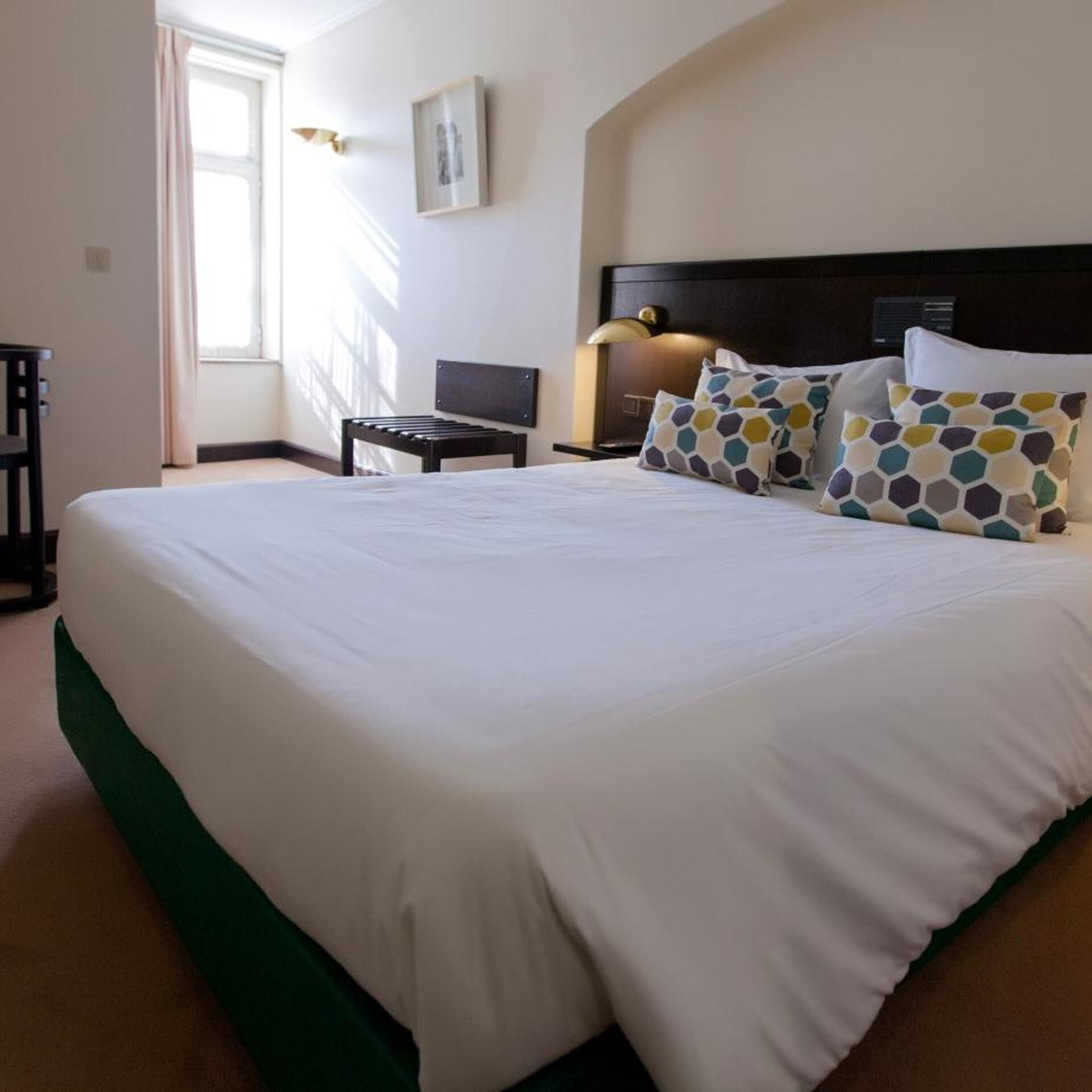 Quarto de hotel com uma cama grande, uma escrivaninha e uma cadeira.
