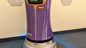 Um robô roxo e prateado com uma tela e uma etiqueta com o nome "HENRY" na parte superior.