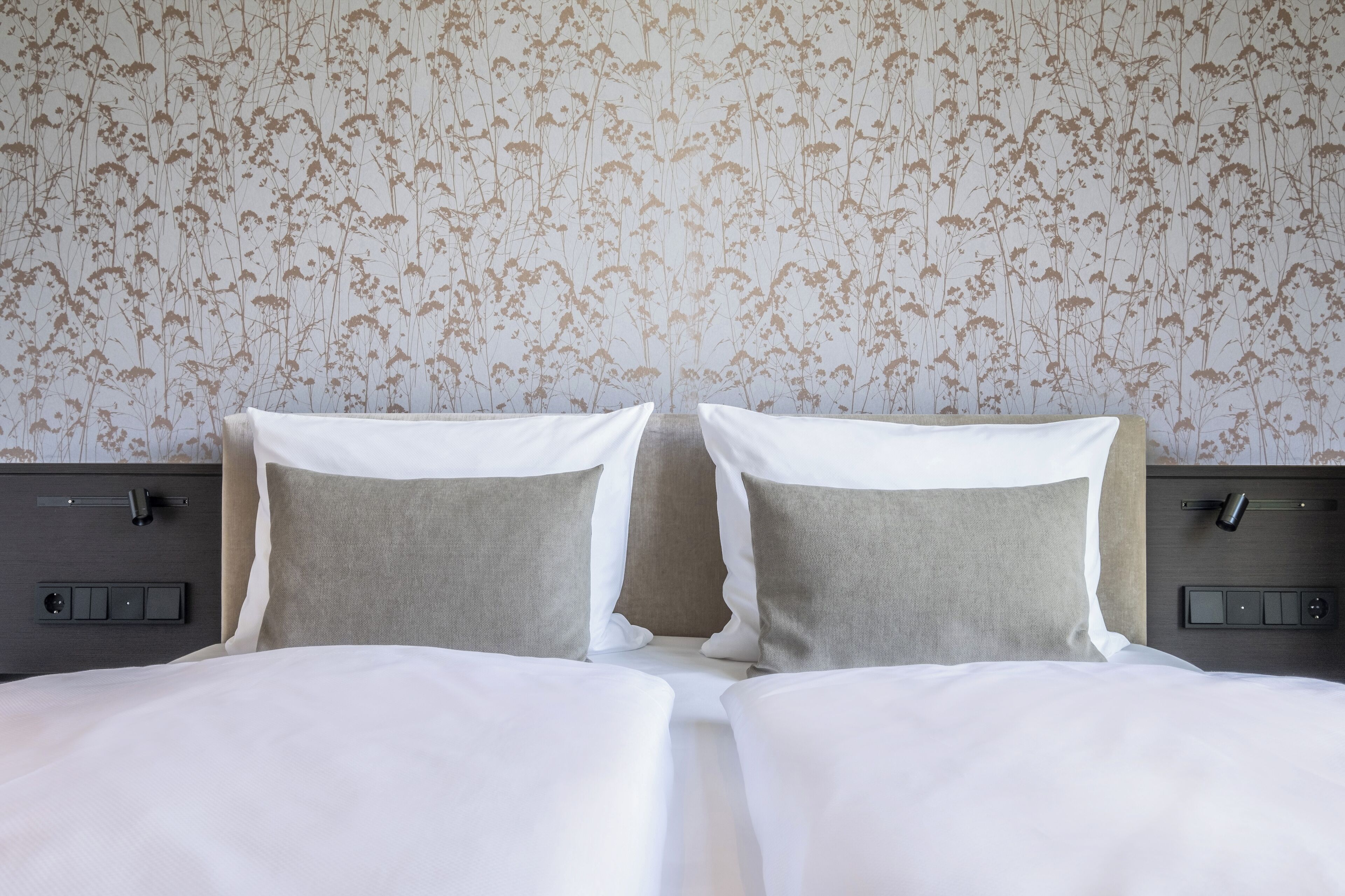 Quarto de hotel com duas camas, cada uma com roupa de cama branca e cinza.