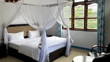 Uma cama com dossel, uma cadeira e uma janela com cortinas.