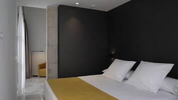 Quarto moderno com uma cama grande, um cobertor amarelo e uma parede escura de destaque.