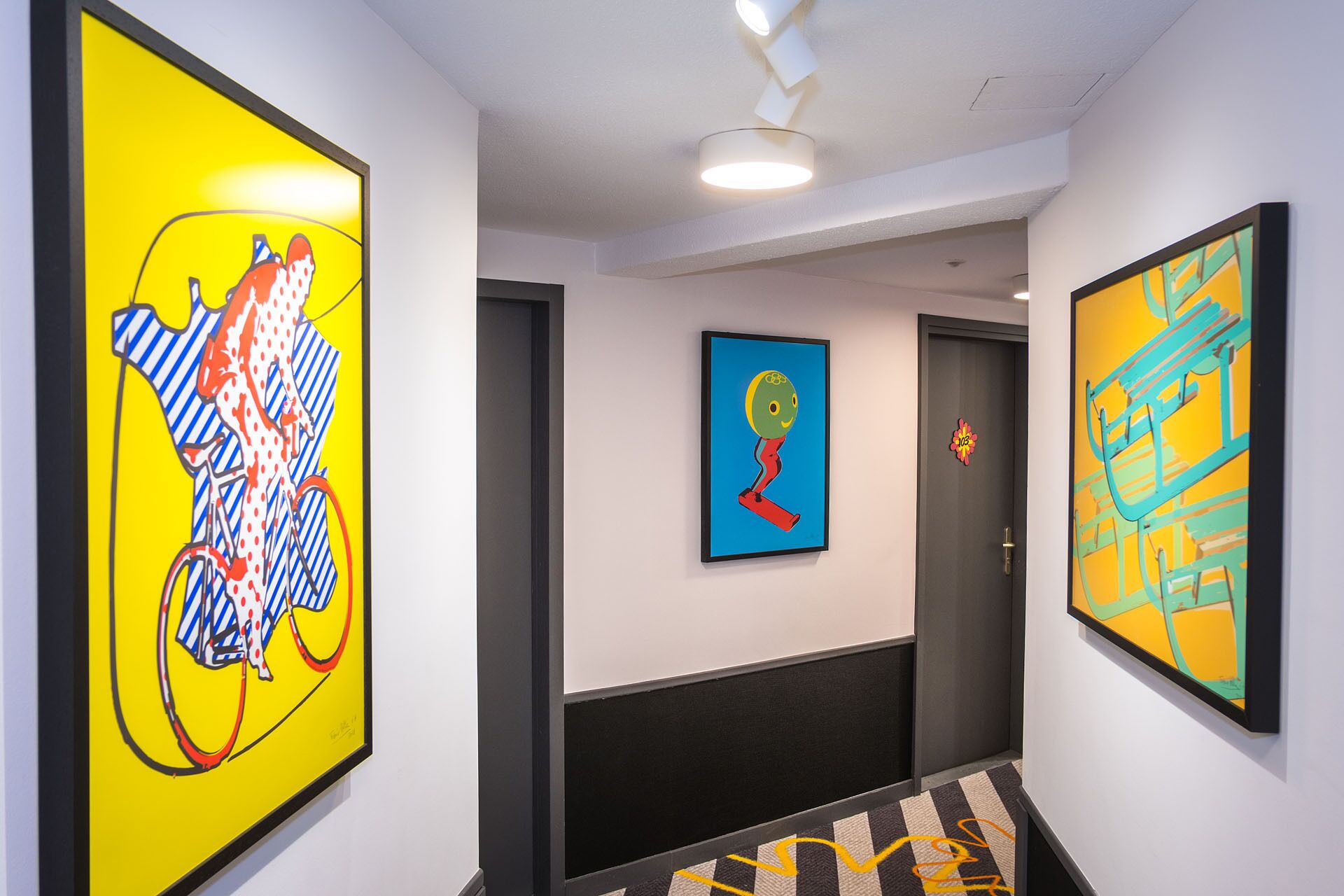 Um corredor com três obras de arte emolduradas nas paredes.