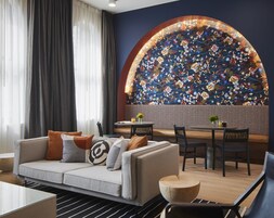 Uma sala de estar moderna com um sofá, cadeiras, uma mesa de jantar e uma parede decorativa com padrão floral.