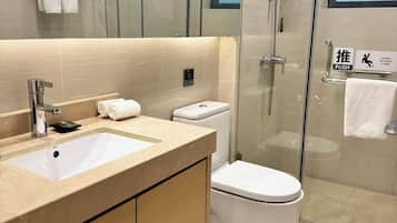 Uma casa de banho moderna com cabine de duche em vidro, lavatório com espelho e sanita.