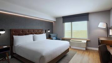 Quarto de hotel moderno com uma cama grande, luminárias de cabeceira, uma escrivaninha e uma janela com vista.