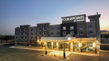 Um hotel com a placa 'Four Points by Sheraton', apresentando um design moderno com vários andares e uma área de entrada coberta.