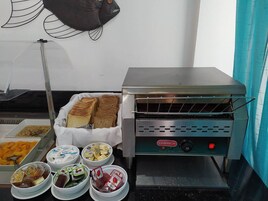Uma cozinha com torradeira, uma bandeja de pão e diversos recipientes de comida.
