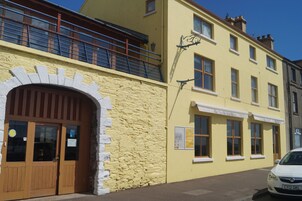 Um edifício amarelo com fachada de pedra, portas de madeira e varanda com grades.