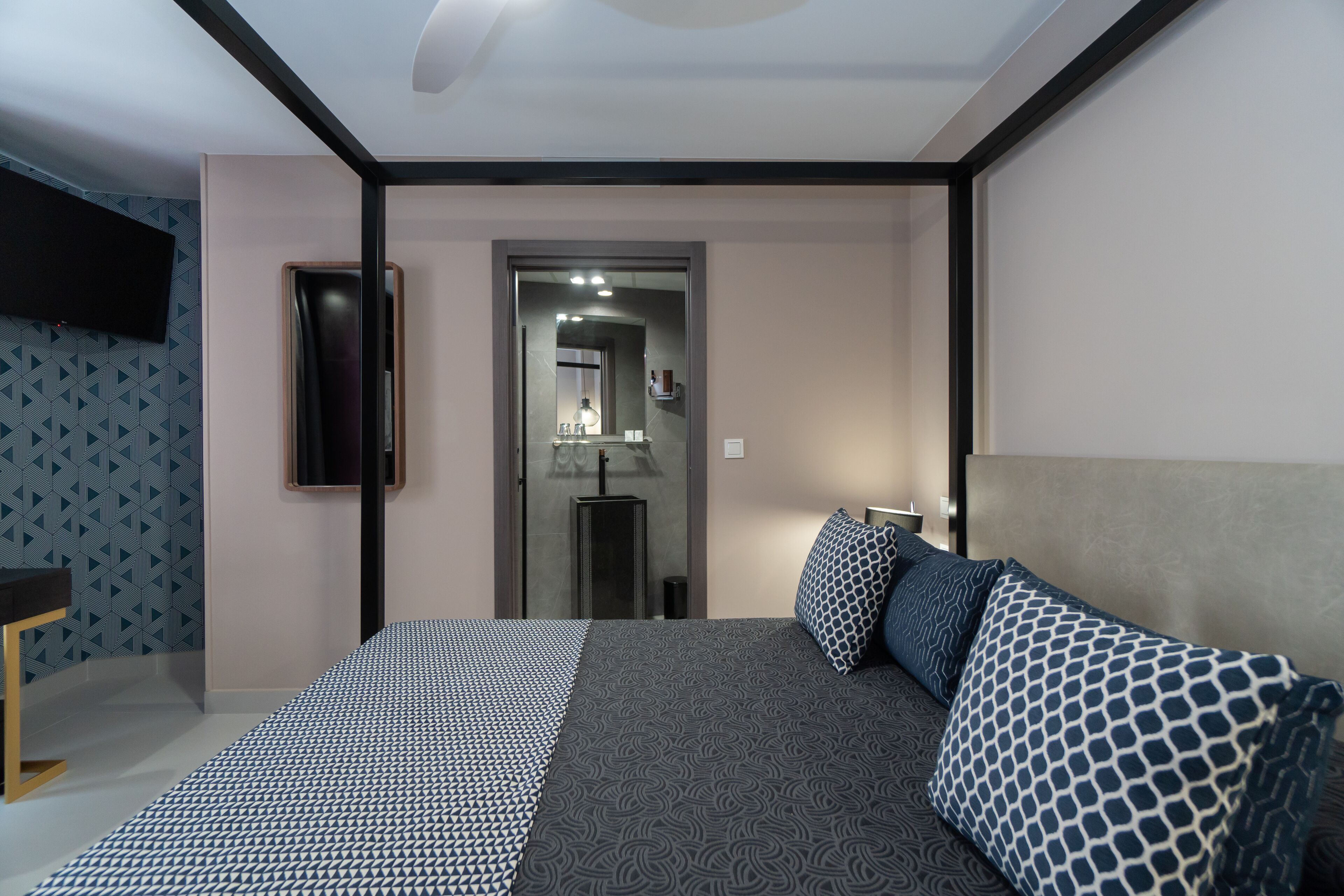 Quarto de hotel moderno com cama grande, televisão de tela plana e espelho.