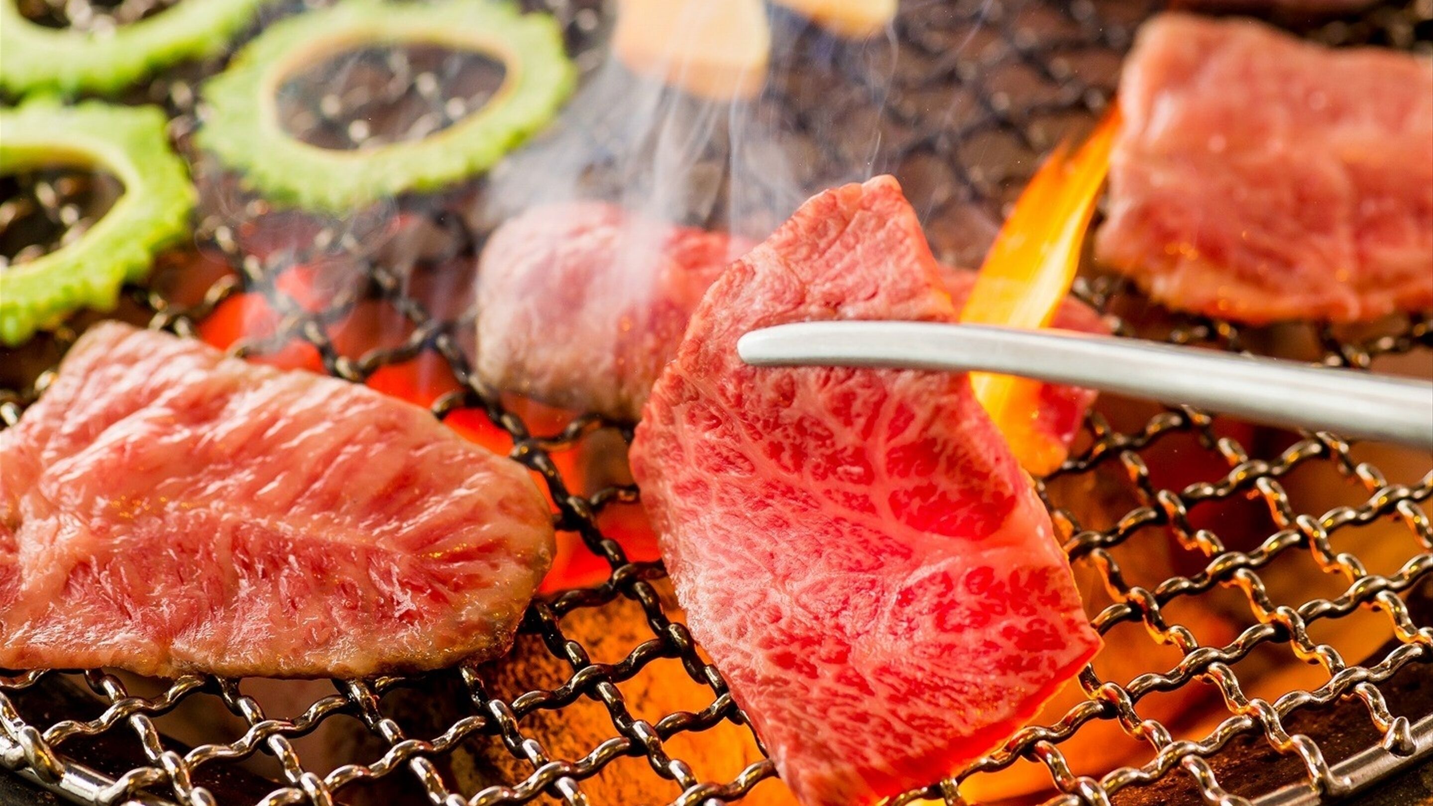 Uma grelha com carnes e legumes diversos a cozinhar.