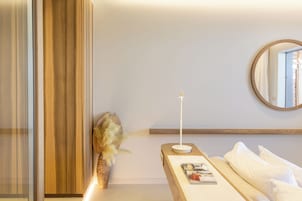 Quarto de hotel com cama, mesa de cabeceira com abajur, espelho e janela com cortinas.