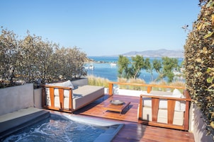 Um terraço com área de estar externa, banheira de hidromassagem e vista para o mar e barcos.