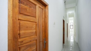 Uma porta de madeira com puxador de metal em um corredor com paredes brancas e chão de azulejos.