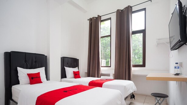 Quarto de hotel com duas camas, uma mesa, uma cadeira e uma televisão.