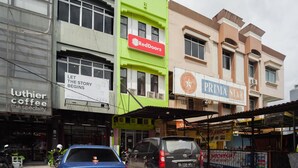 Vista da rua com edifícios, incluindo a placa RedDoorz, a cafeteria Luthier Coffee e o estabelecimento PRIMA STAR.