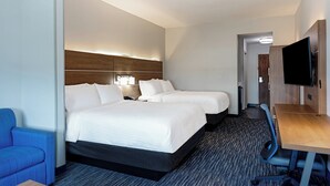 Quarto de hotel com duas camas, uma escrivaninha, uma cadeira, uma televisão e a porta do banheiro.