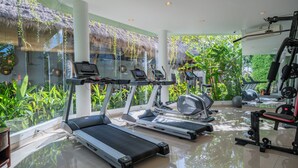 Uma academia com esteiras, elípticos e equipamentos de musculação, com amplas janelas dando para áreas verdes.