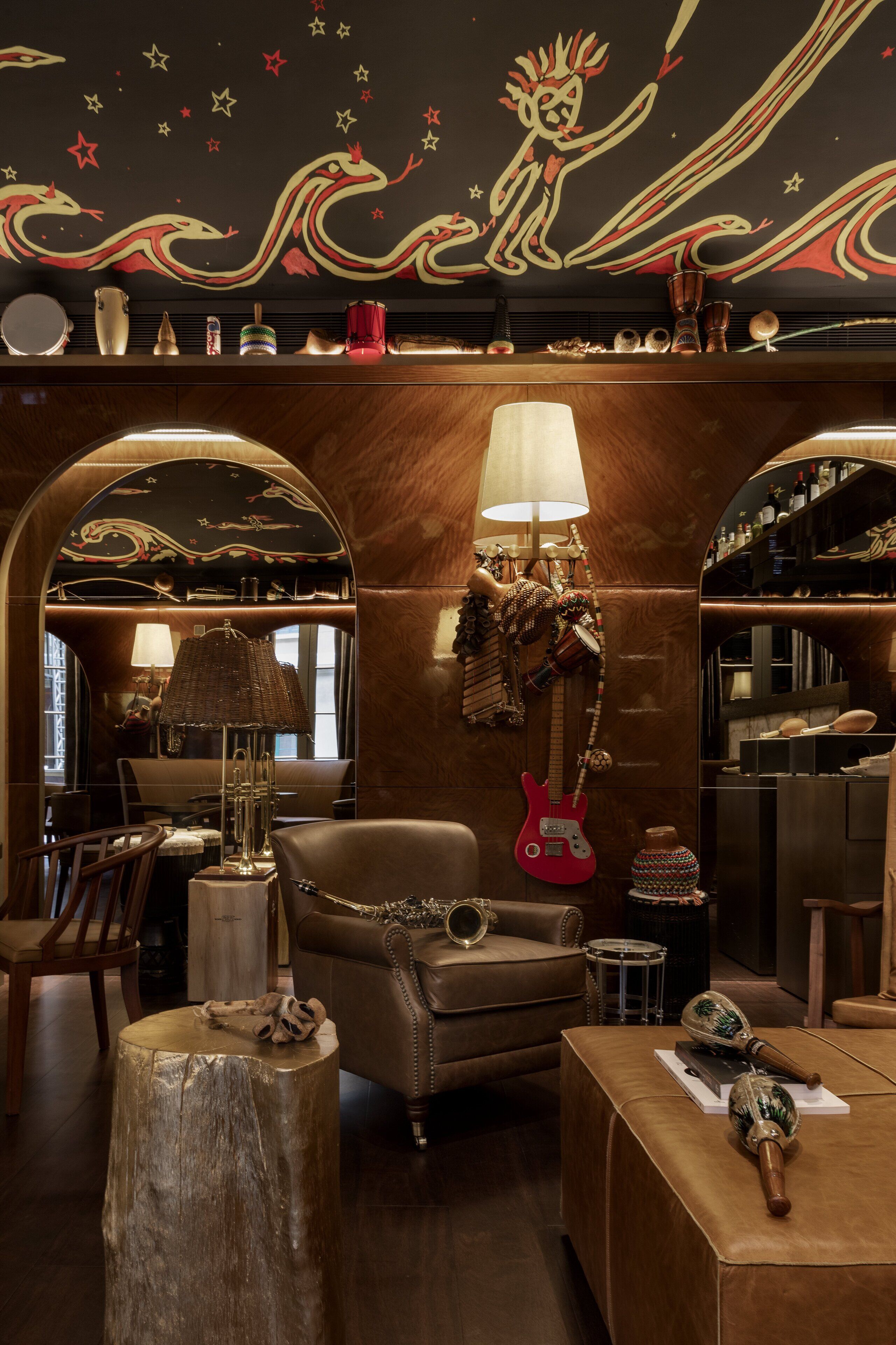 Uma área de estar aconchegante com uma poltrona de couro, uma guitarra elétrica vermelha e uma mesa de centro de madeira.