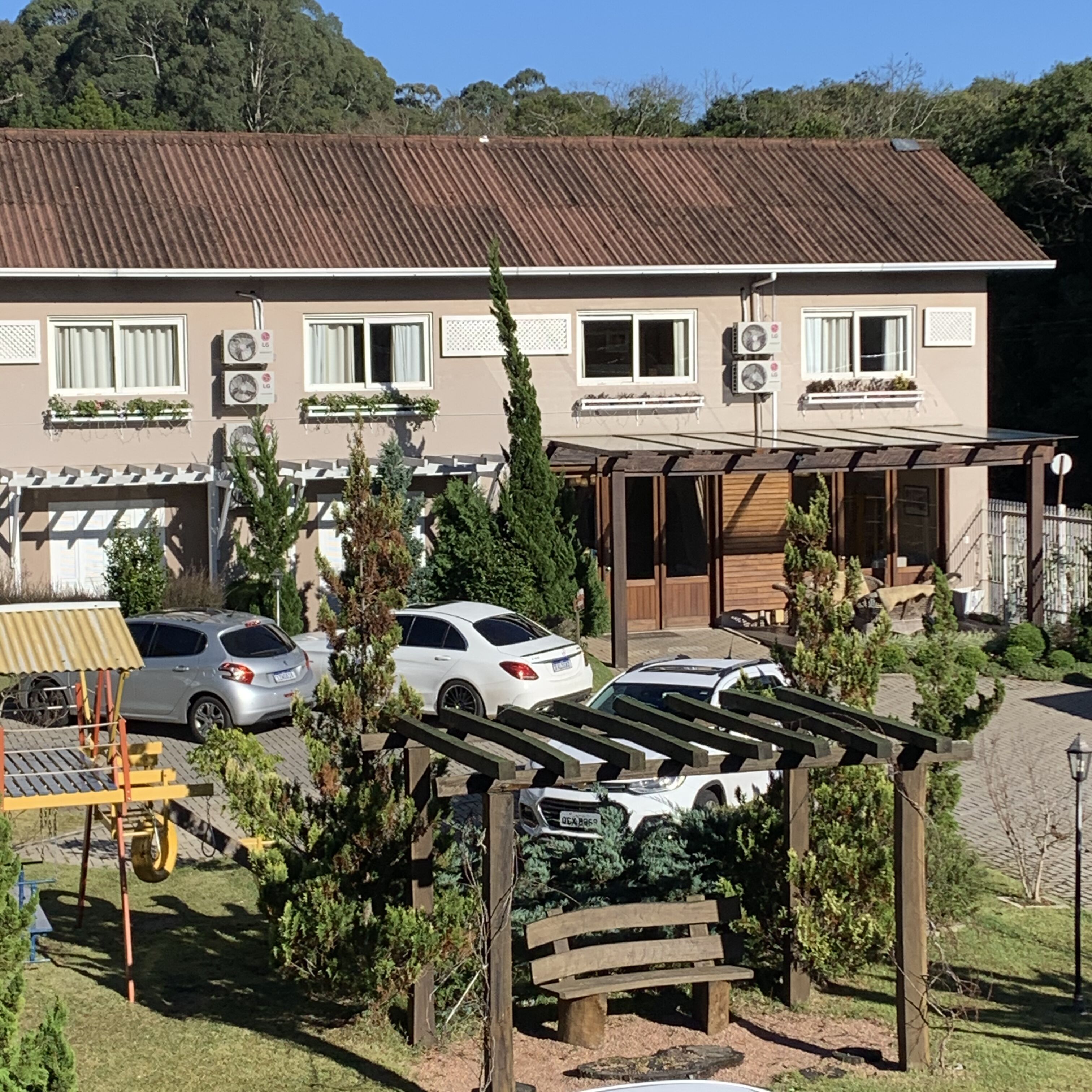 Um edifício com telhado marrom, várias janelas e área de estar externa.