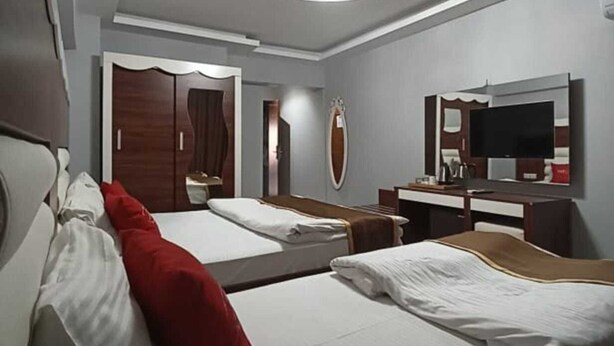 Quarto de hotel com duas camas, televisão, escrivaninha e espelho.