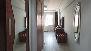 Um corredor com um guarda-roupa de madeira, um espelho e um banco.