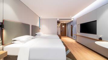 Quarto de hotel moderno com uma cama grande, uma TV, um banheiro com pia e um espelho.