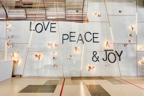 Parede decorada com as palavras 'LOVE PEACE & JOY' e luzes em forma de borboletas.