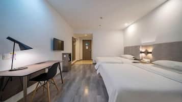 Quarto de hotel com escrivaninha, duas camas, televisão e abajur.