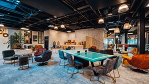 Uma sala de reuniões moderna com uma mesa grande, assentos confortáveis e iluminação em estilo industrial.