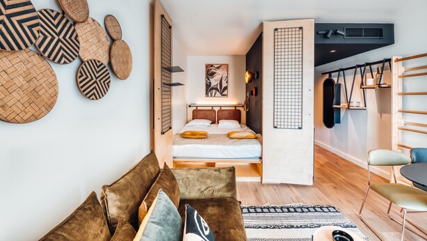 Quarto moderno com cama, sofá e área de jantar.