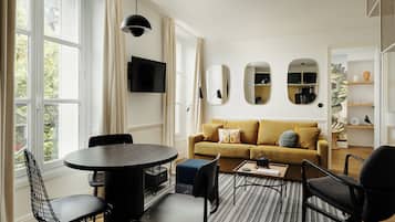Uma sala de estar moderna com sofá, cadeiras, mesa de centro e televisão.