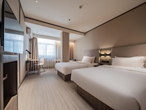 Quarto de hotel com duas camas, uma mesa e uma televisão.