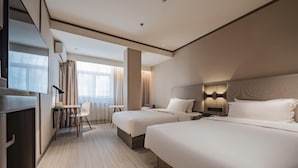 Quarto de hotel com duas camas, uma escrivaninha e televisão.